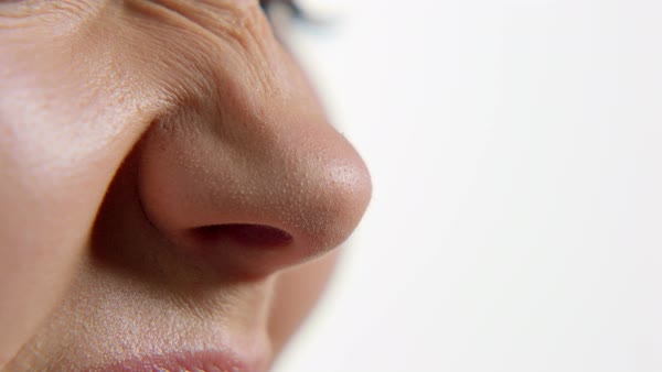 Close-up of a woman wrinkling up the skin on her nose. - Stock Video Footage - Dissolve