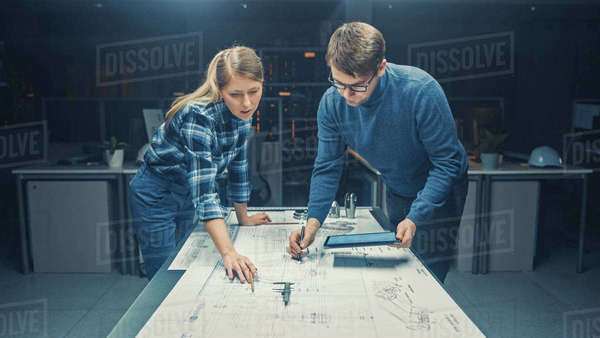 In the Dark Industrial Design Engineering Facility Male and Female Engineers Talk and Work on a ...
