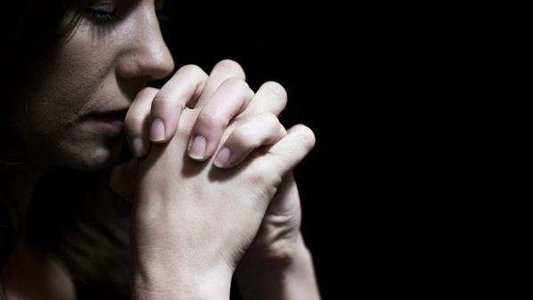 Praying with hands clasped together on dark black background - Stock ...