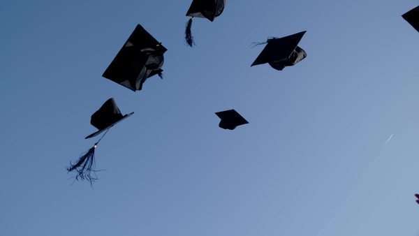 Graduation caps are tossed into the air on a bright sunny day and then ...