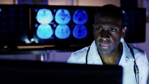 Doctor working late at night in a room full of computer screens is ...