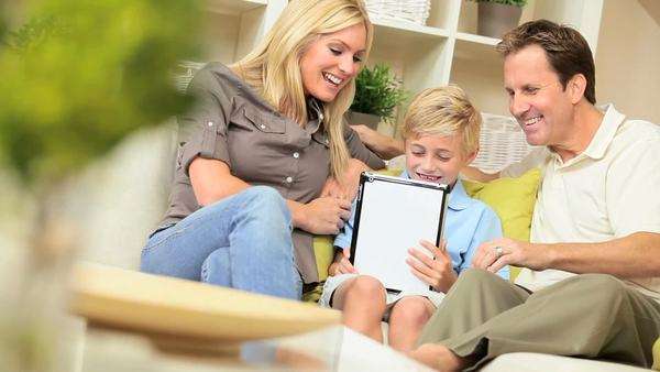 Young Caucasian family talking to family via video web chat on a ...