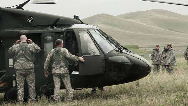 Shot from field of landed Black Hawk helicopter and soldiers exiting ...