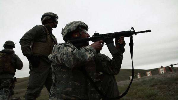 Static shot of soldier shooting M4 rifle at target range while kneeling ...