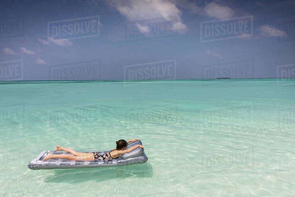 Girl laying, floating on inflatable raft in tropical blue ocean - Stock ...
