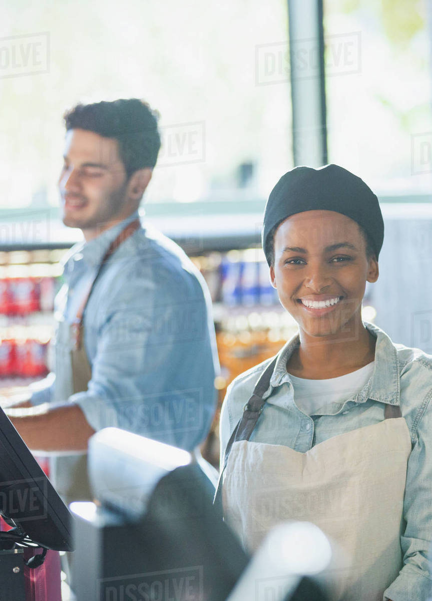 Portrait smiling young female cashier working at grocery store market ...