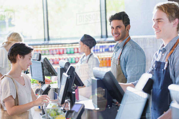Portrait smiling, confident young male cashier working at grocery store ...