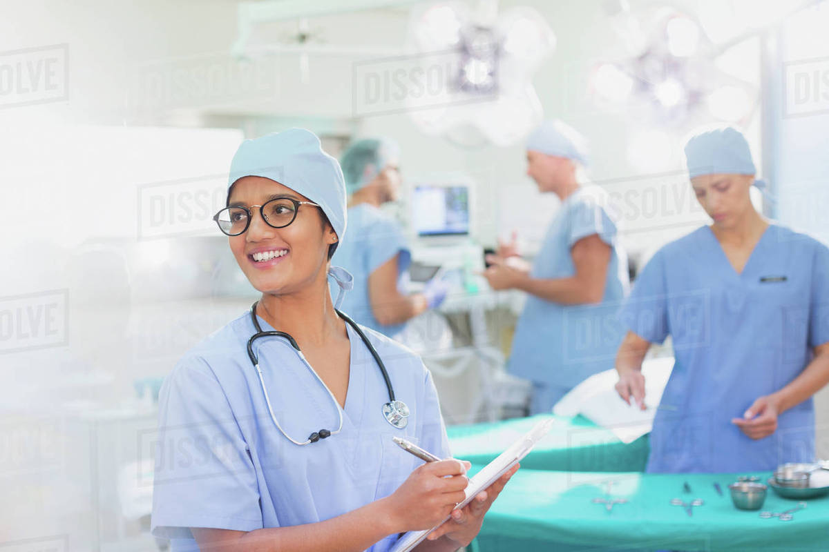 Smiling female surgeon with clipboard in operating room - Royalty-free ...