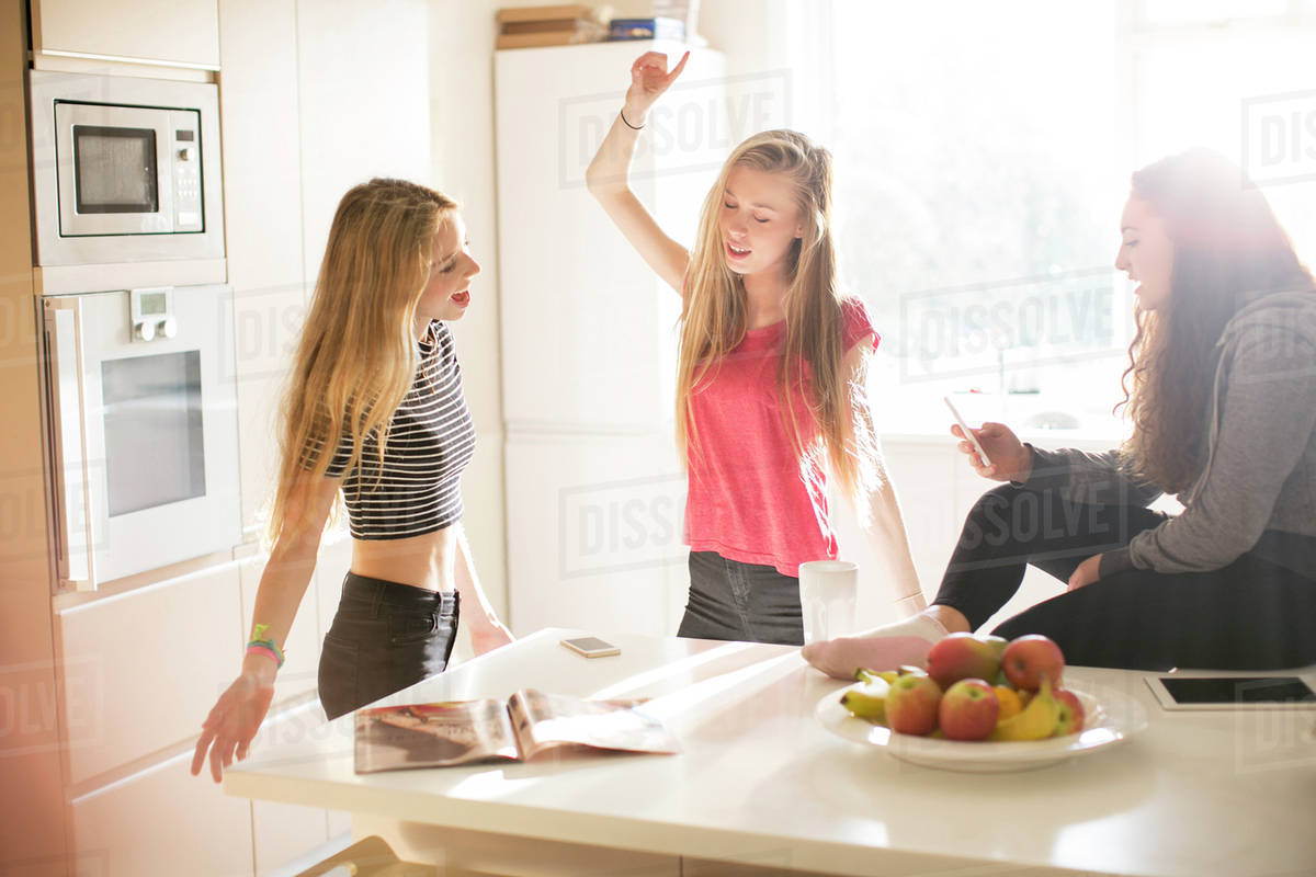 Teenage girls dancing in sunny kitchen - Royalty-free Stock Photo ...
