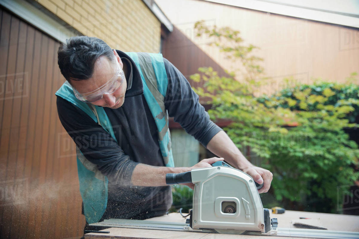 Construction worker using table saw in driveway - Royalty-free Stock ...