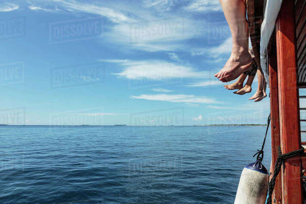 Bare feet dangling over sunny ocean dock, Maldives - Royalty-free Stock ...