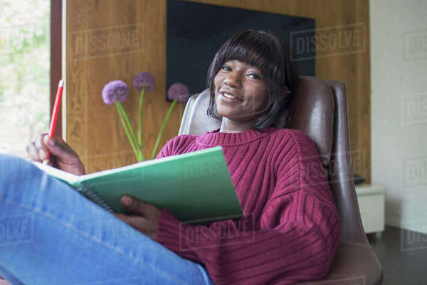 Portrait happy young woman journaling - Royalty-free Stock Photo | Dissolve