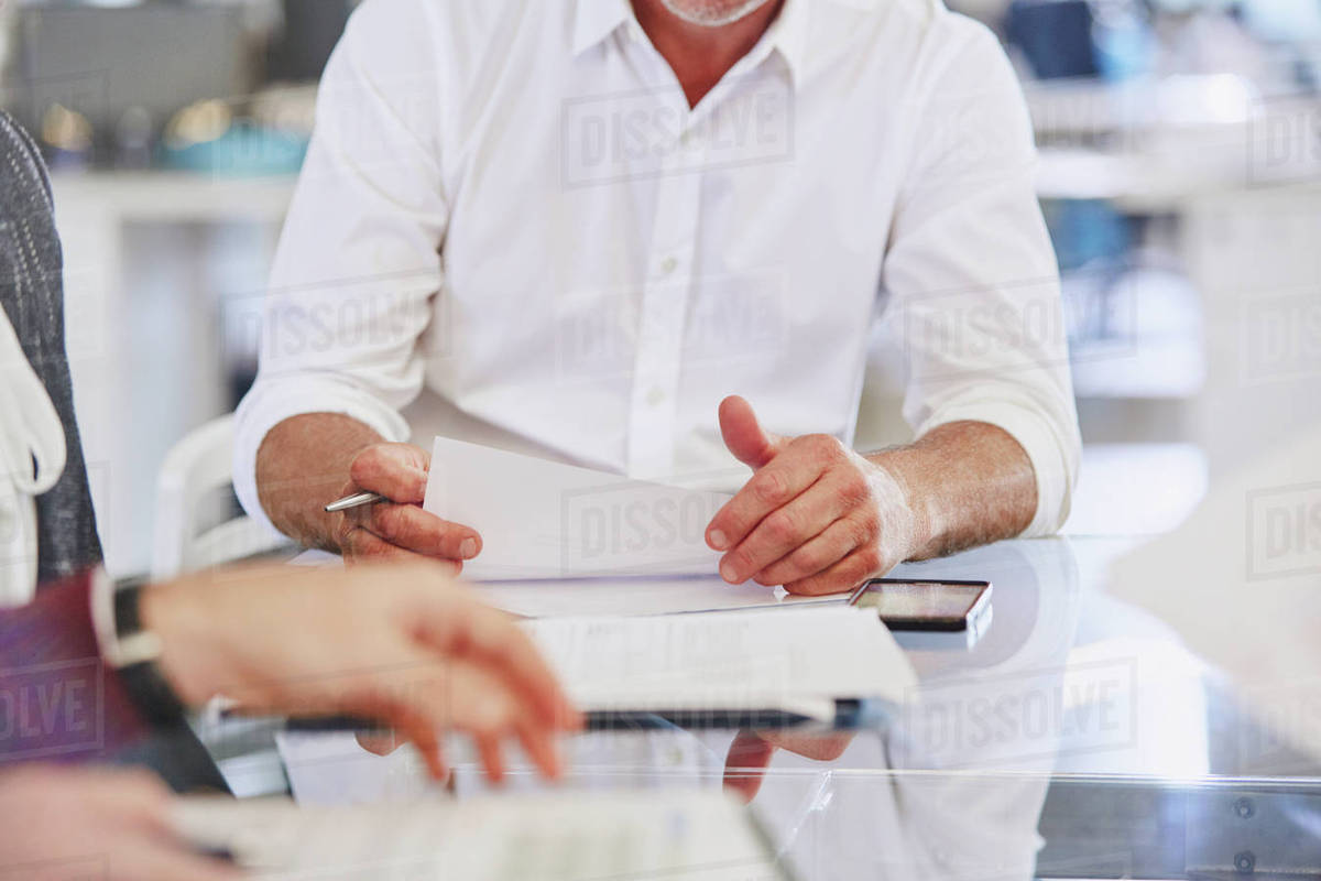 Business people reviewing paperwork in meeting - Stock Photo - Dissolve
