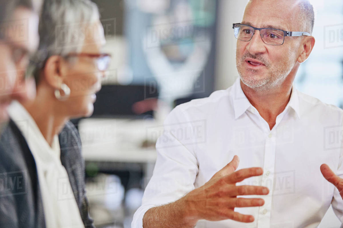 Businessman explaining to colleagues in meeting - Stock Photo - Dissolve