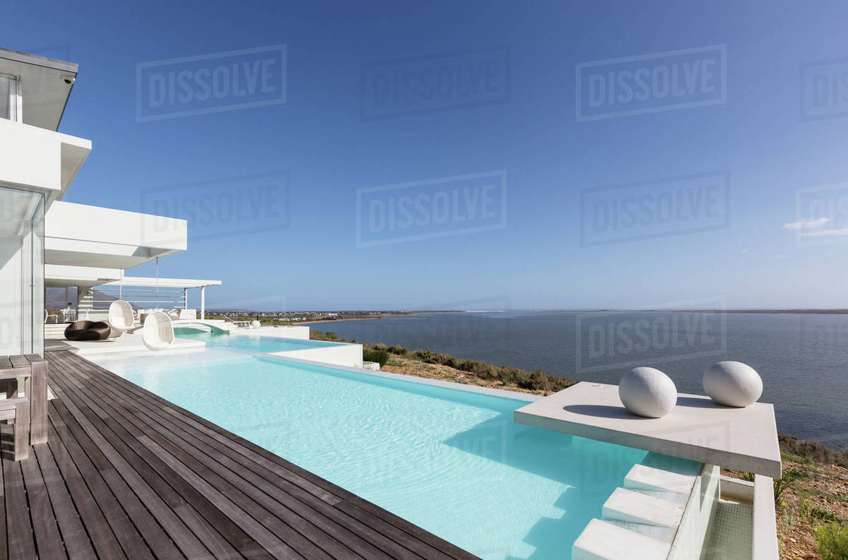 Sunny, tranquil modern luxury home showcase exterior infinity pool with ...