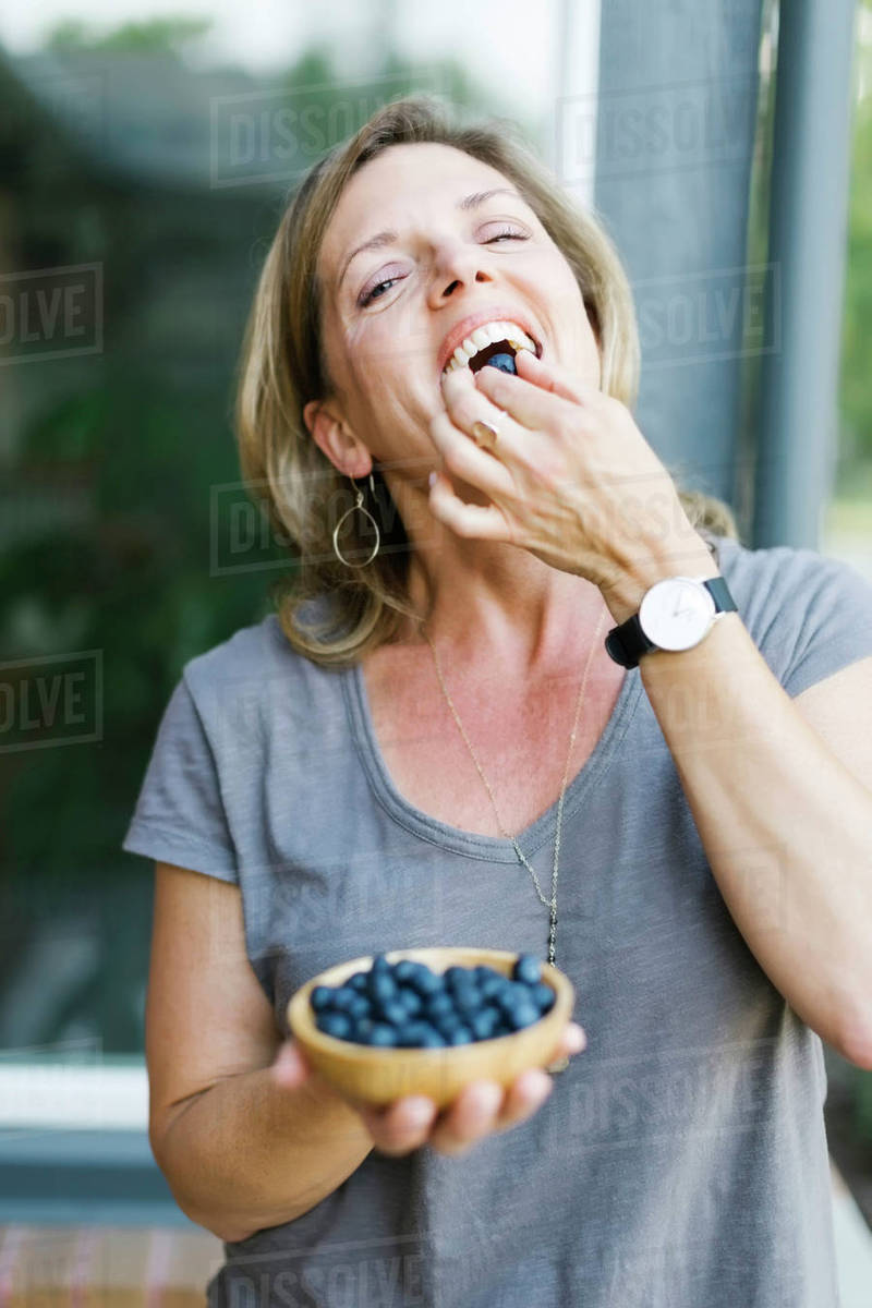 Woman eating blueberries - Royalty-free Stock Photo | Dissolve