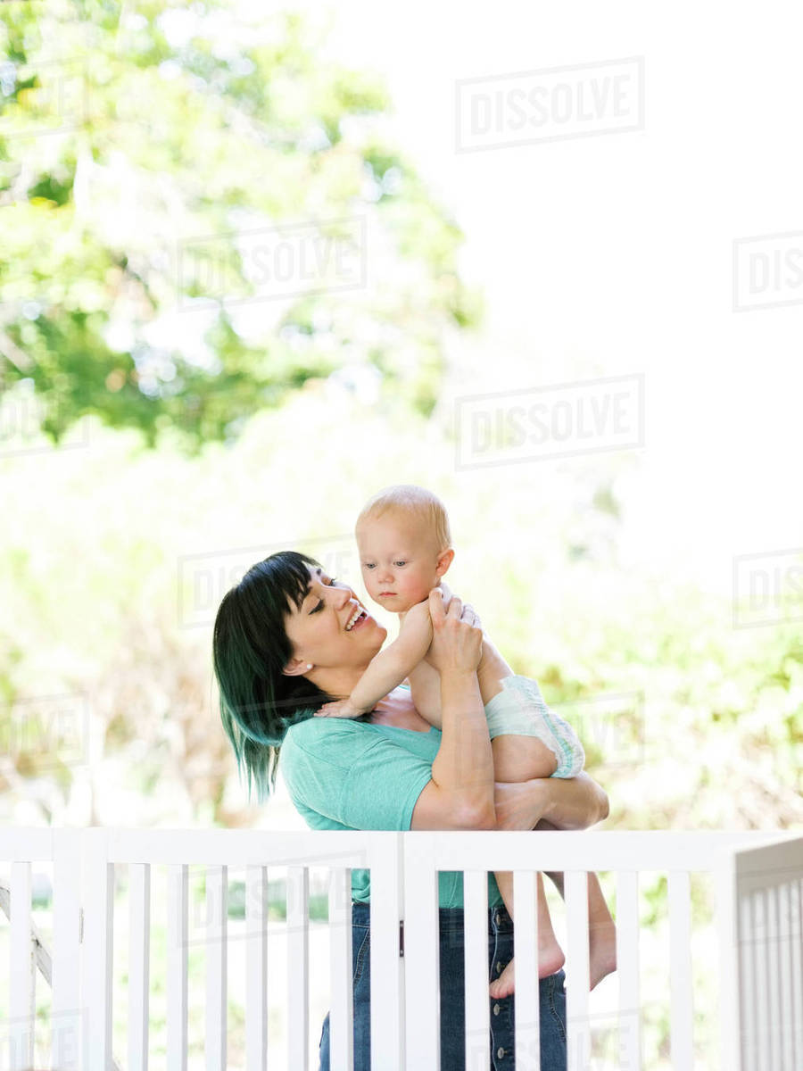 Mother carrying baby boy on porch - Stock Photo - Dissolve