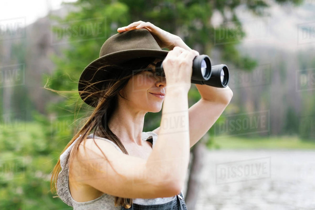 Woman using binoculars - Stock Photo - Dissolve