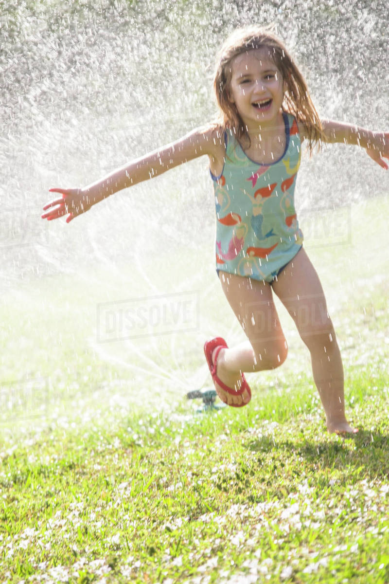 Girl splashing in sprinkler water on lawn - Royalty-free Stock Photo ...