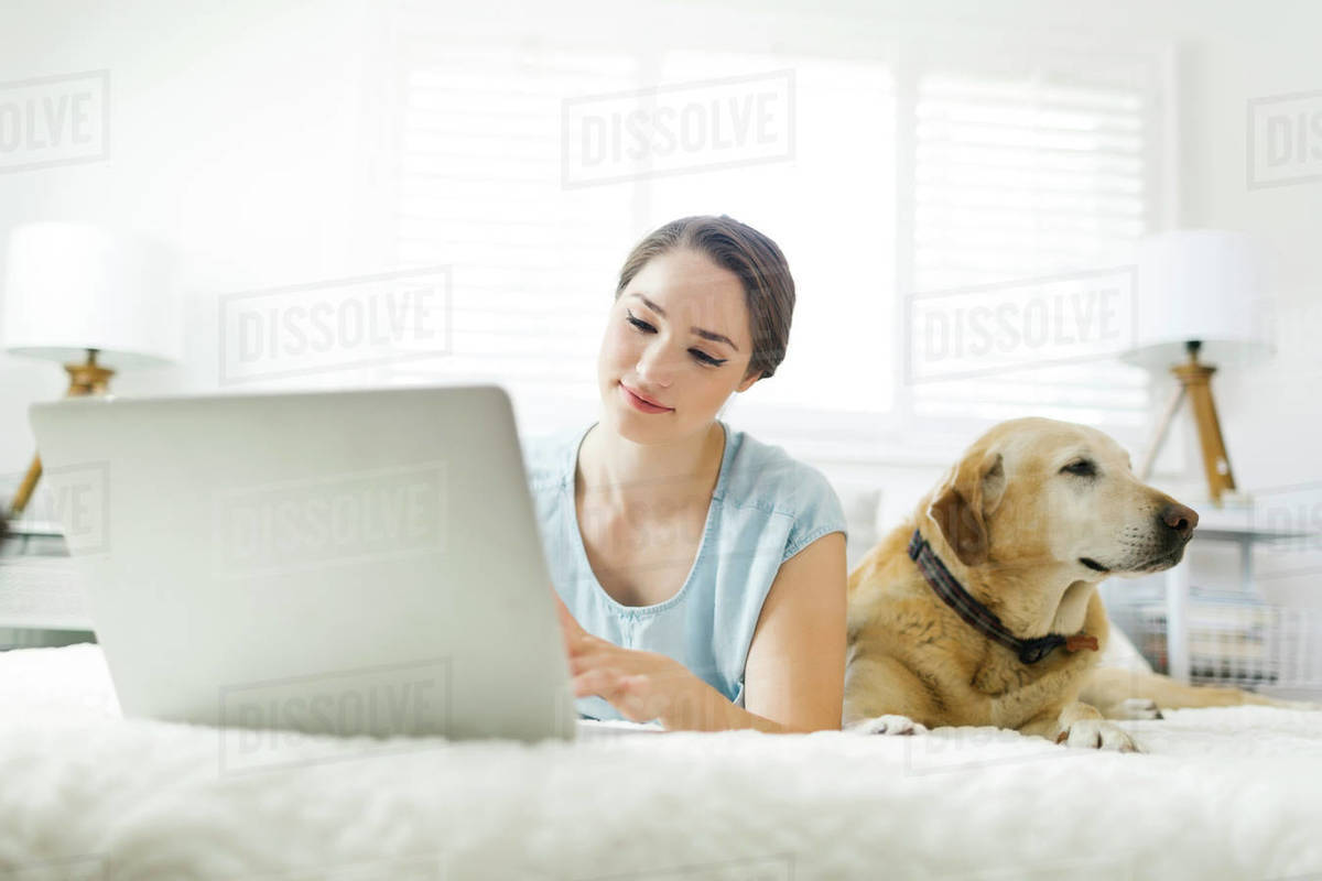 Woman using laptop with dog - Royalty-free Stock Photo | Dissolve