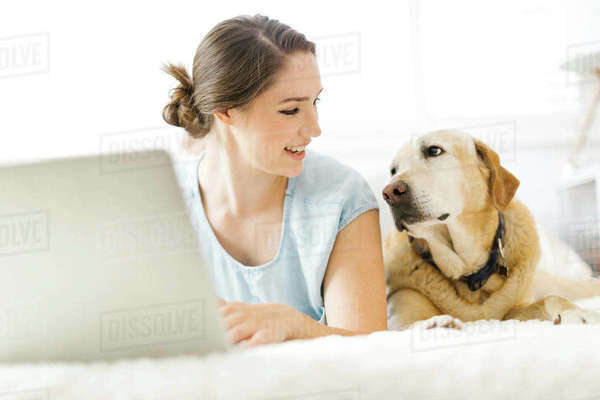 Woman using laptop with dog - Stock Photo - Dissolve