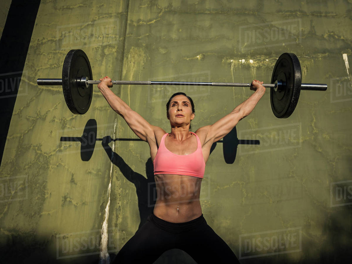 Woman weight lifting with barbell - Royalty-free Stock Photo | Dissolve
