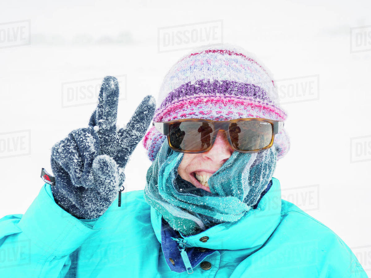 Smiling woman making peace gesture in snow - Royalty-free Stock Photo ...