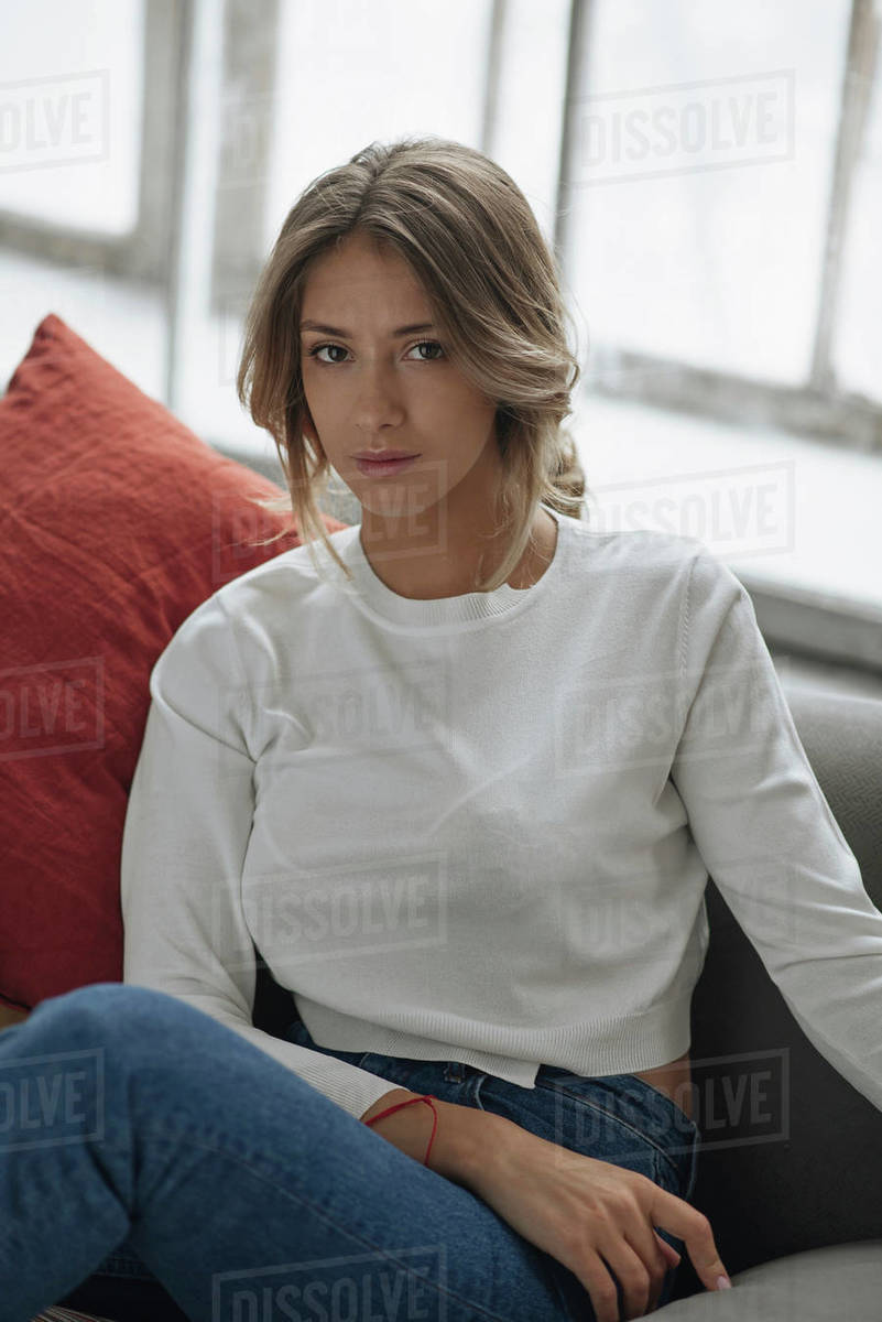 Young woman wearing white sweater on sofa - Royalty-free Stock Photo ...