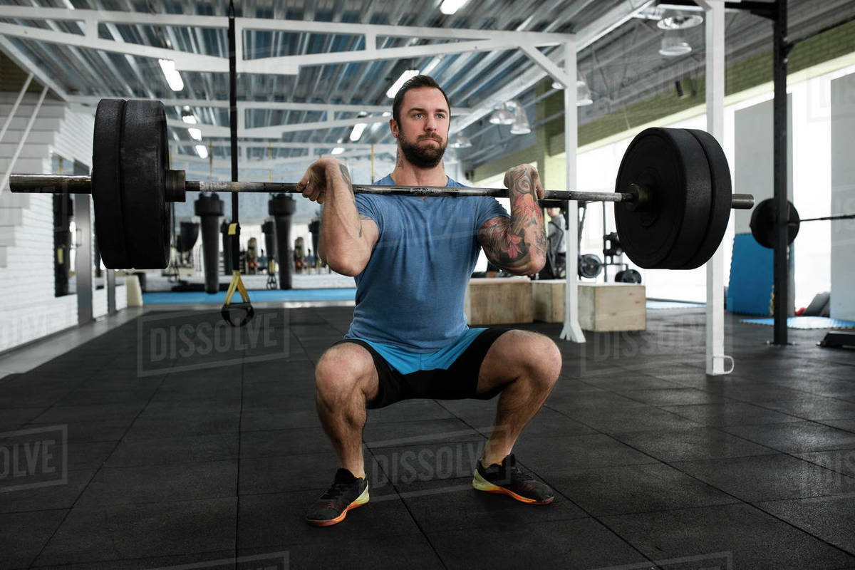 Mid adult man weight lifting in gym - Royalty-free Stock Photo | Dissolve