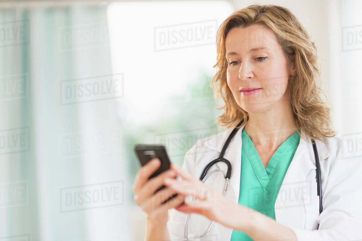 Female doctor using phone - Royalty-free Stock Photo | Dissolve