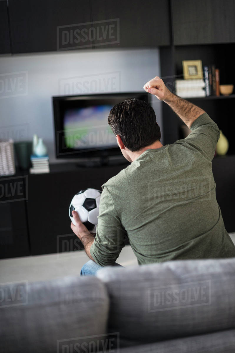 Rear view of man watching sports on tv - Royalty-free Stock Photo ...