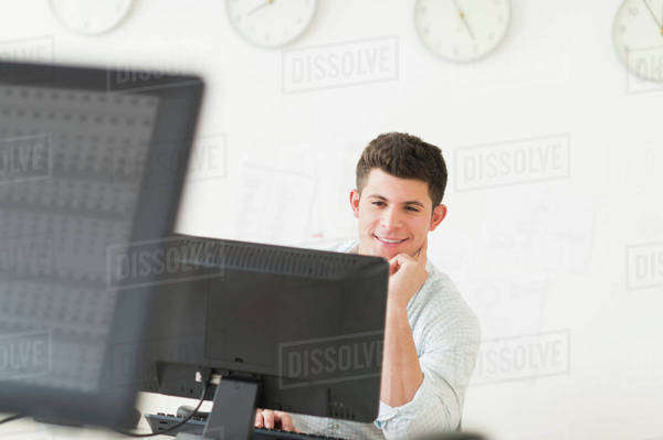 Young man sitting in front of desk and working - Royalty-free Stock ...