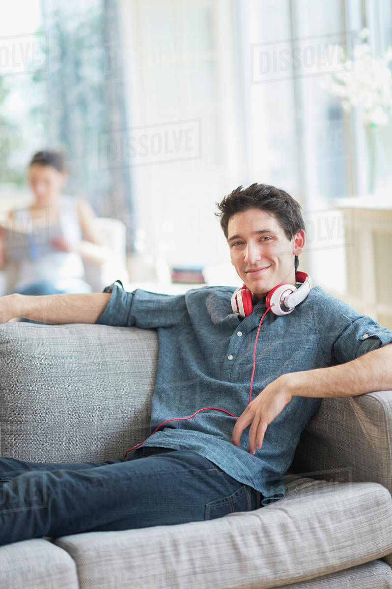 Man sitting on sofa, woman in background - Stock Photo - Dissolve