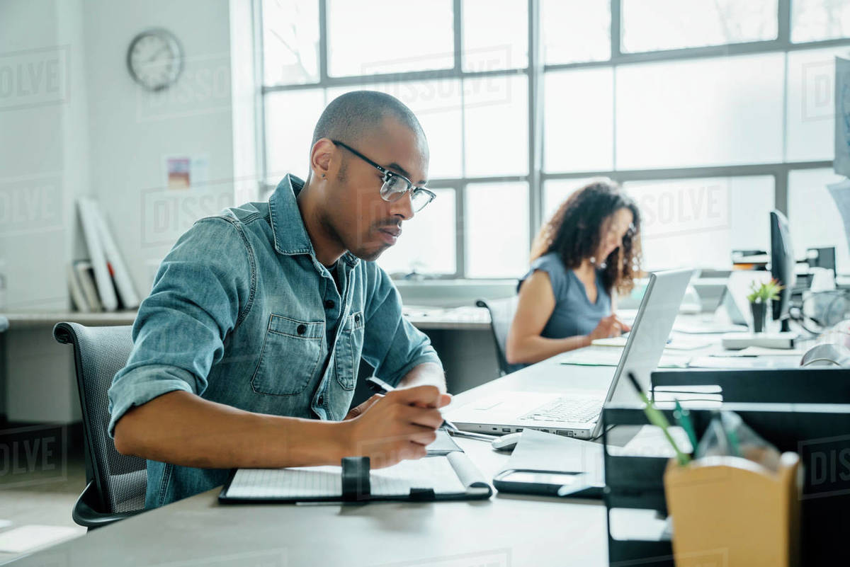 Man holding pen using laptop in office - Stock Photo - Dissolve