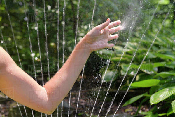 Woman's hand touching spray from sprinkler - Royalty-free Stock Photo ...