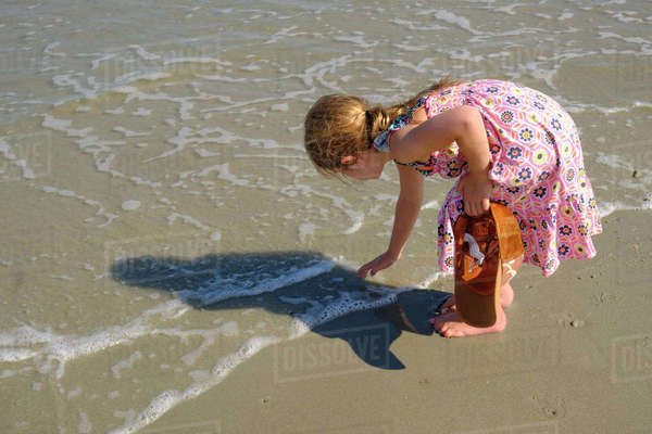 Girl bending over on beach - Stock Photo - Dissolve