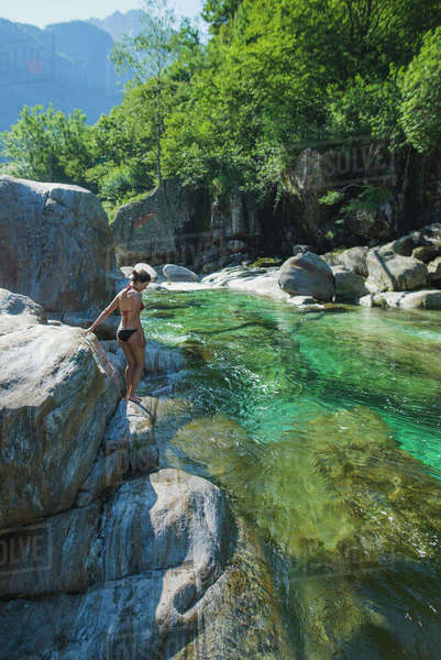 Woman wearing bikini on rock by river - Royalty-free Stock Photo | Dissolve