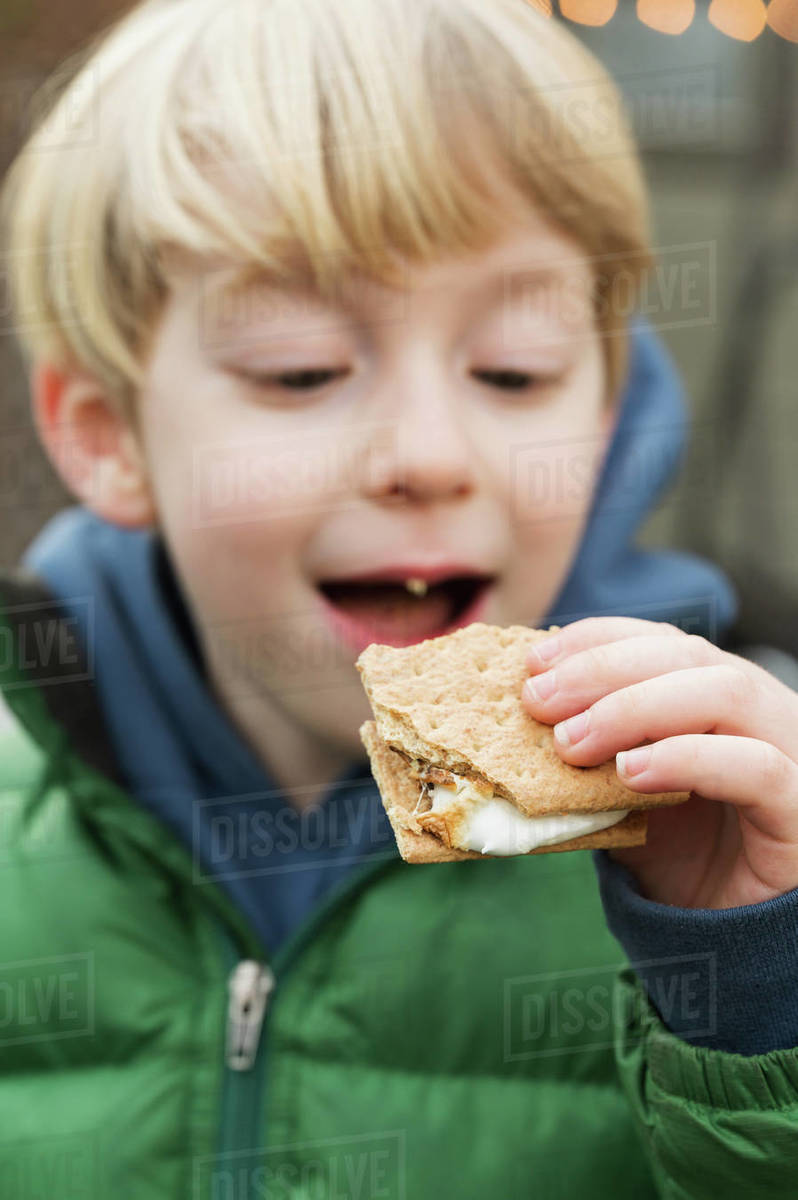 Cute boy (4-5) eating cracker with marshmallow - Stock Photo - Dissolve