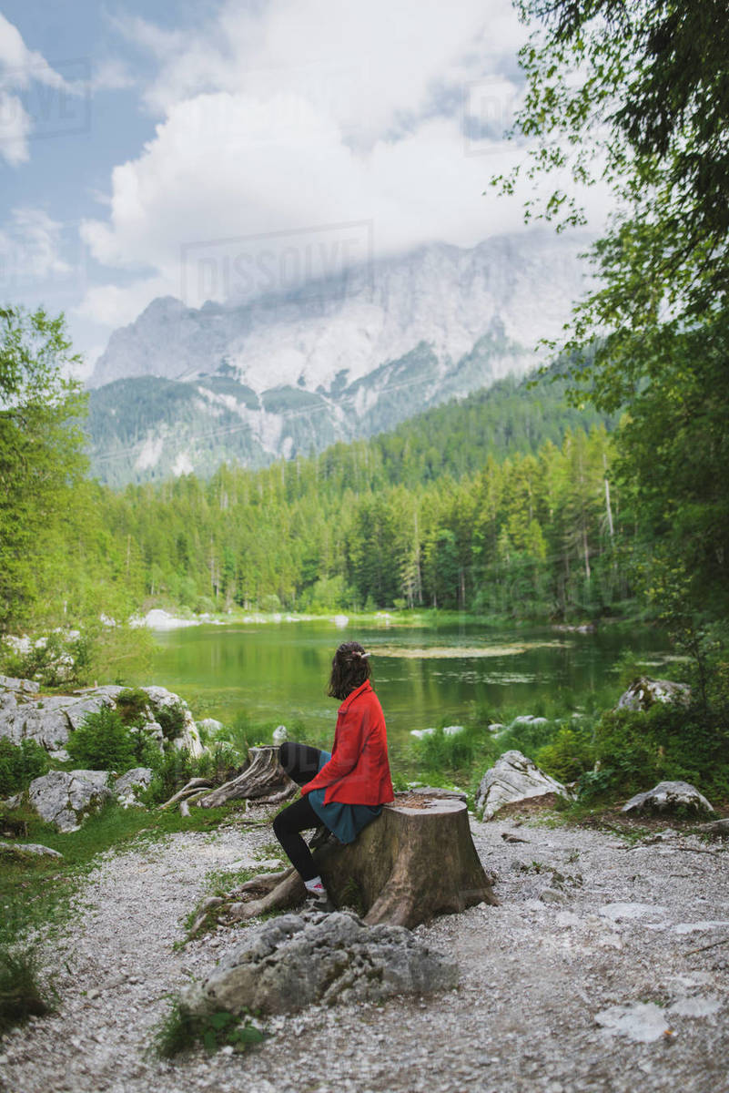 Germany, Bavaria, Eibsee, Woman sitting by Frillensee lake - Royalty ...