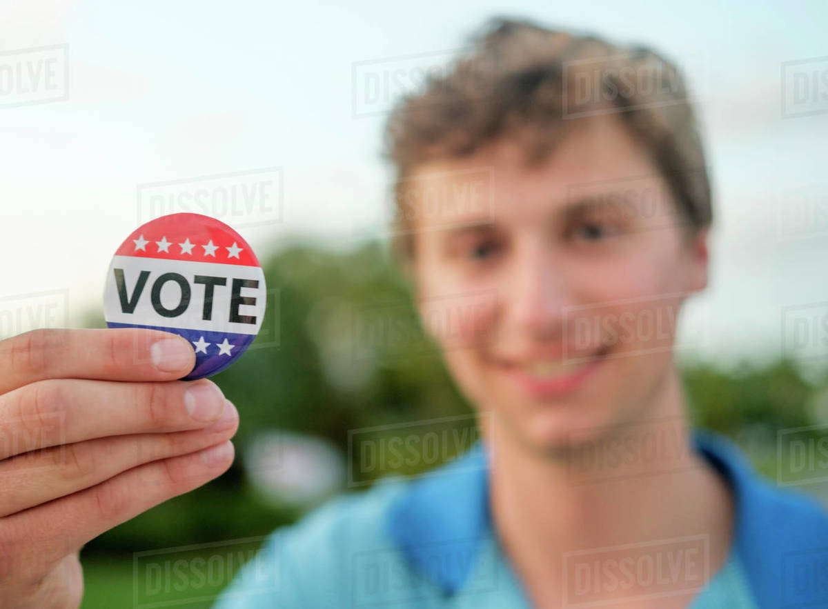 Smiling man holding vote button - Royalty-free Stock Photo | Dissolve