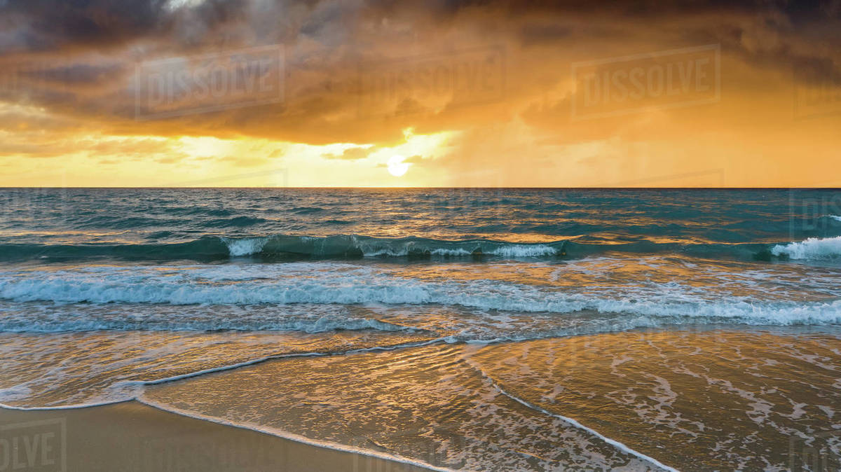 Beach under dramatic sky at sunset - Royalty-free Stock Photo | Dissolve