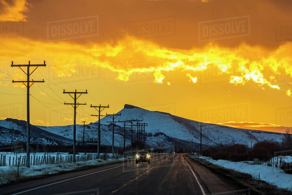 Car on road under dramatic sky at sunrise - Royalty-free Stock Photo ...