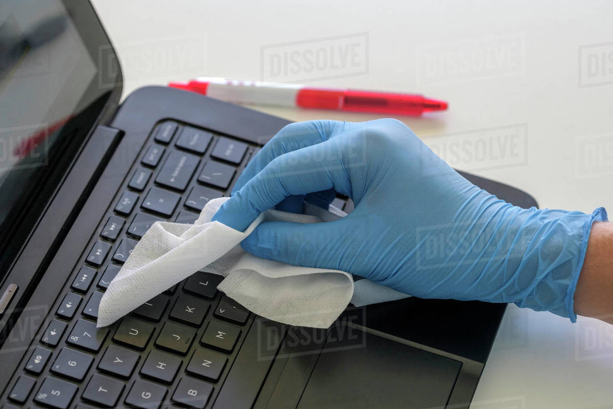 Person wearing blue surgical glove cleaning keyboard of laptop - Stock ...
