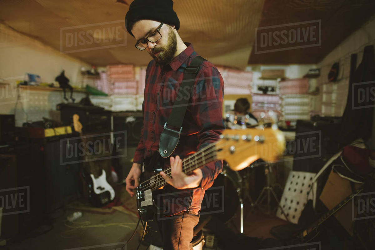 Young man playing bass guitar during rehearsal in garage - Royalty-free ...