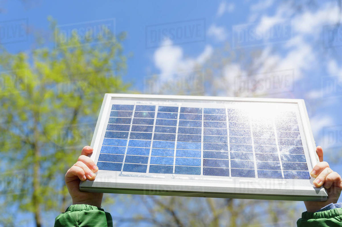 Close-up of boys (4-5) hands holding solar panel against sky - Royalty ...