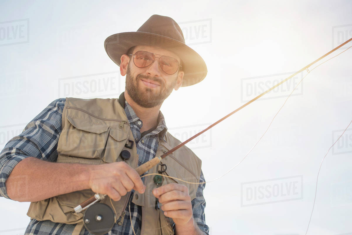 Portrait of man holding fishing rod - Stock Photo - Dissolve