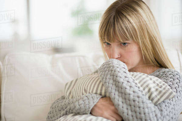 Woman sitting on sofa and thinking - Royalty-free Stock Photo | Dissolve
