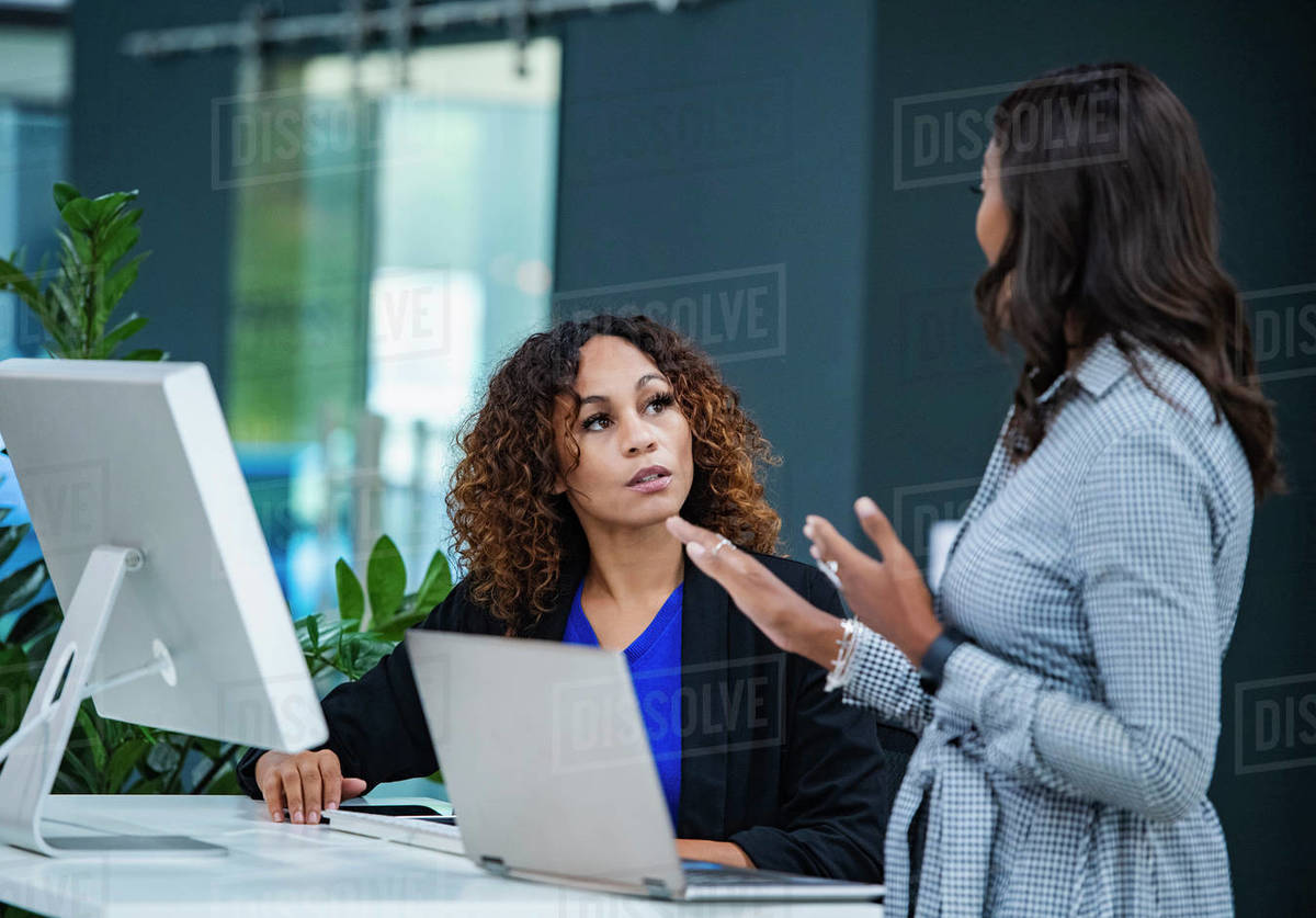Two women talking in office - Stock Photo - Dissolve