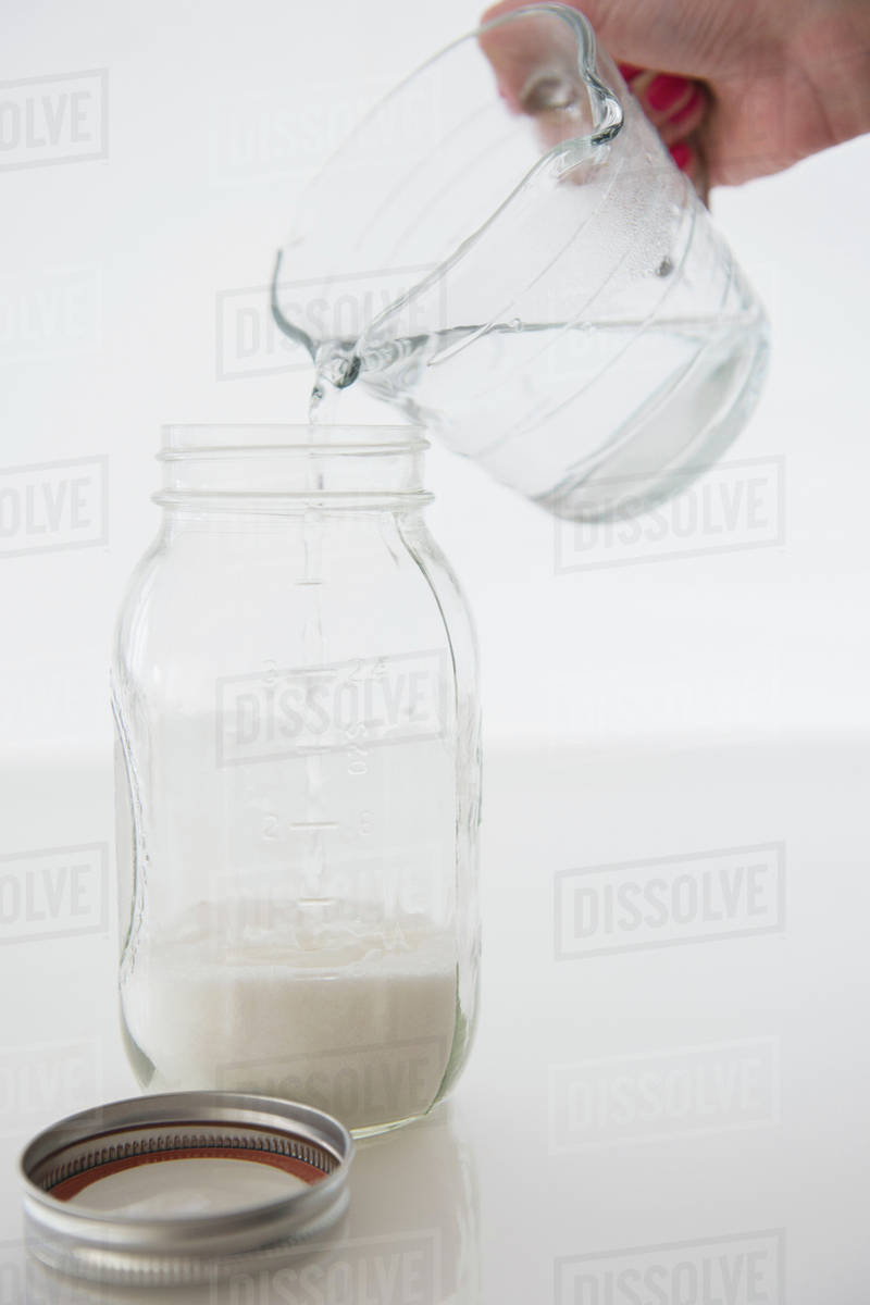 Woman mixing milk with water - Royalty-free Stock Photo | Dissolve