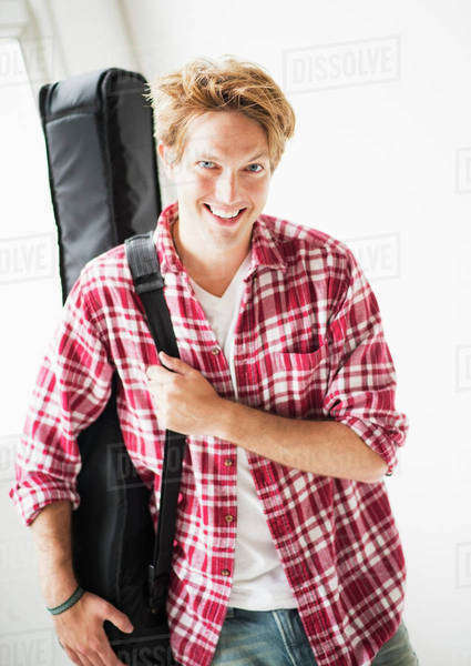 Portrait of man carrying guitar bag - Royalty-free Stock Photo | Dissolve